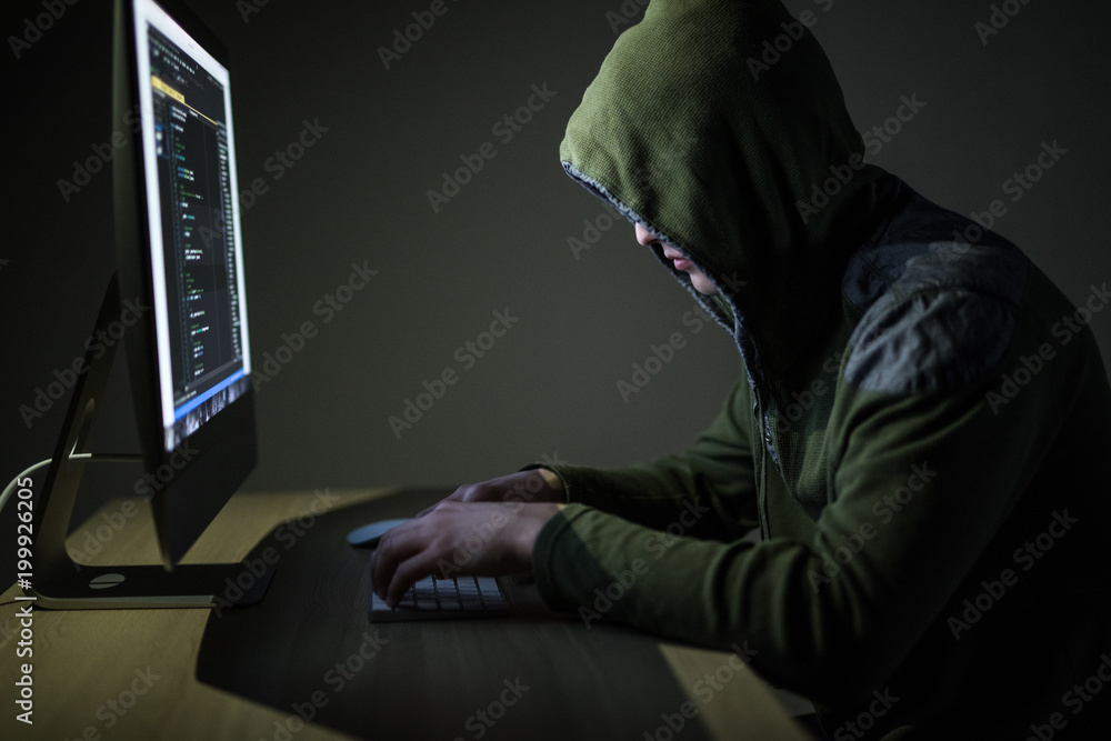 Hooded computer hacker stealing information with pc in Dark room ...