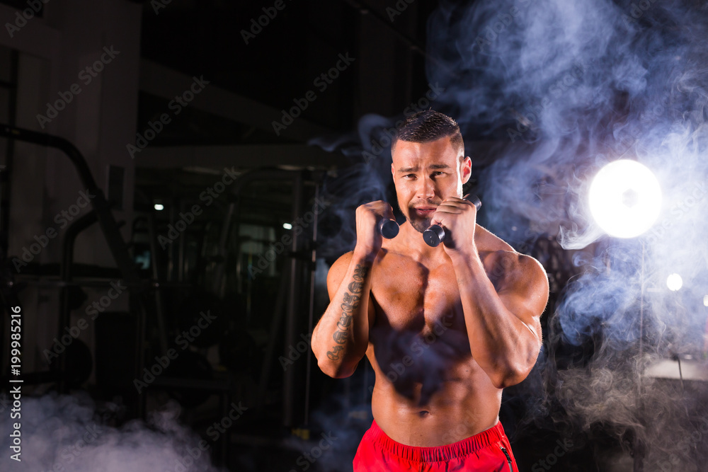 Powerful man doing boxing exercises, making direct hit with dumbbells ...