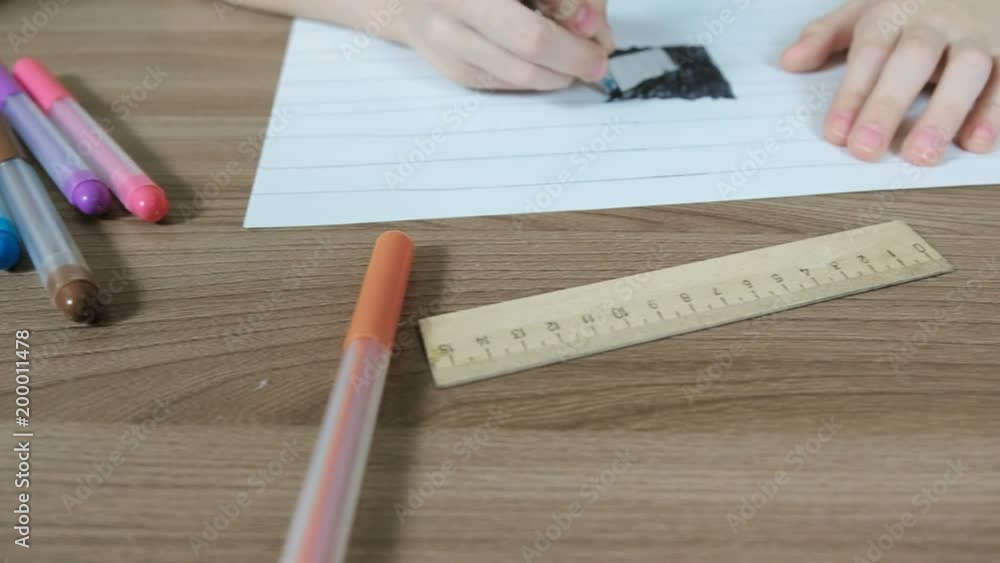 Felt pens, paper, ruler on table and drawing boy's hands close-up ...