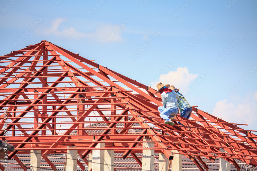 welder workers installing steel frame structure of the house roof at ...