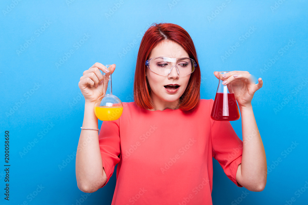 Confused chemist woman with two tubes with yellow and red liquid in her ...