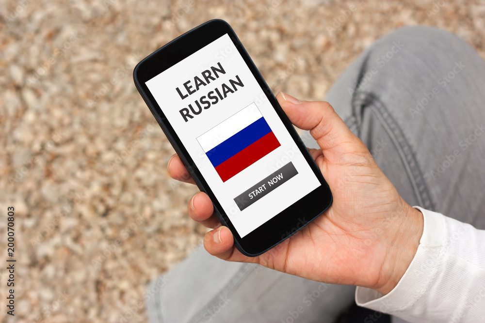 Hand holding smart phone with learn Russian concept on screen. All ...