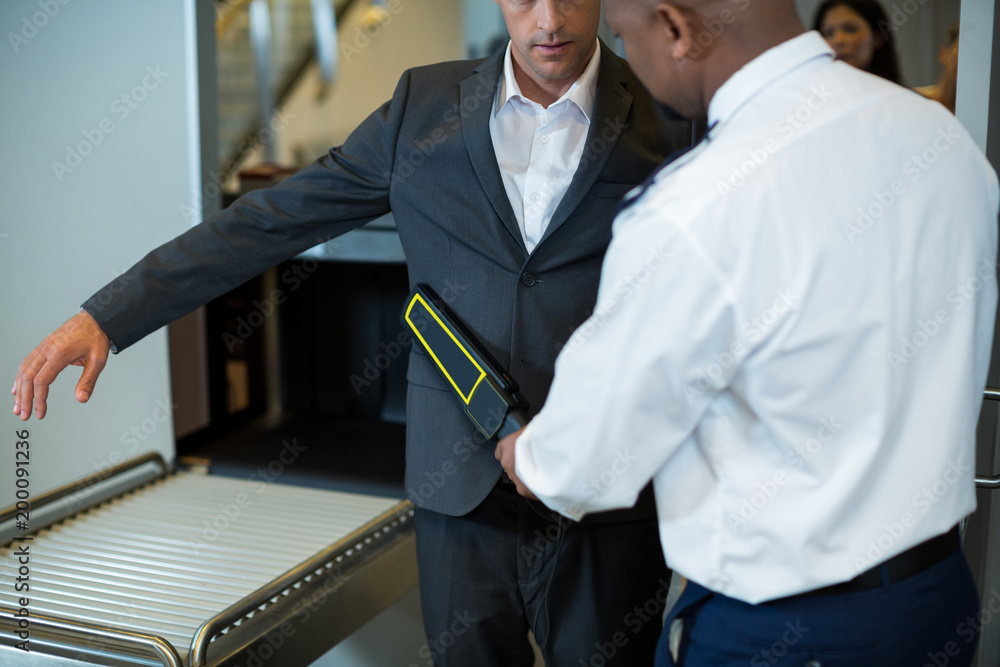 Airport security officer using a hand held metal detector to check a ...