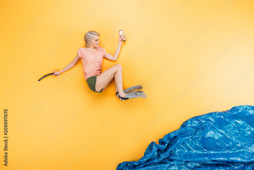 beautiful young woman in flippers jumping in imagine sea on yellow ...