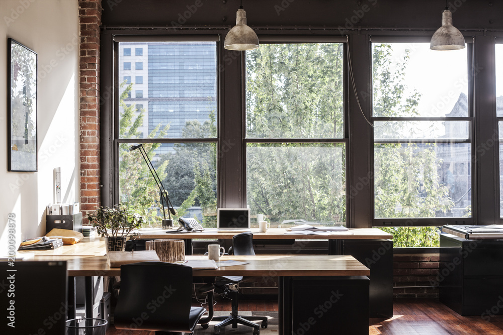 Creative office interior. View through a window to trees and city ...