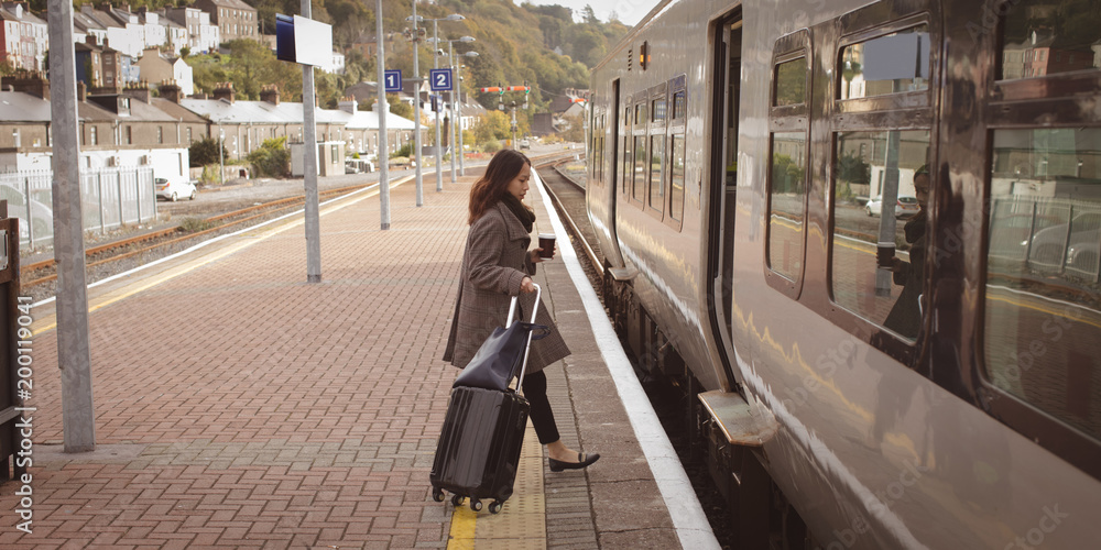 Woman getting in the train with luggage Stock Photo | Adobe Stock