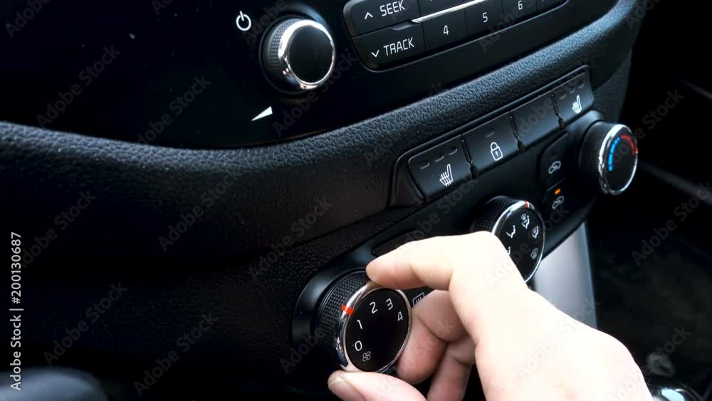 Regulation of the temperature in the car. Man sets the air condition ...
