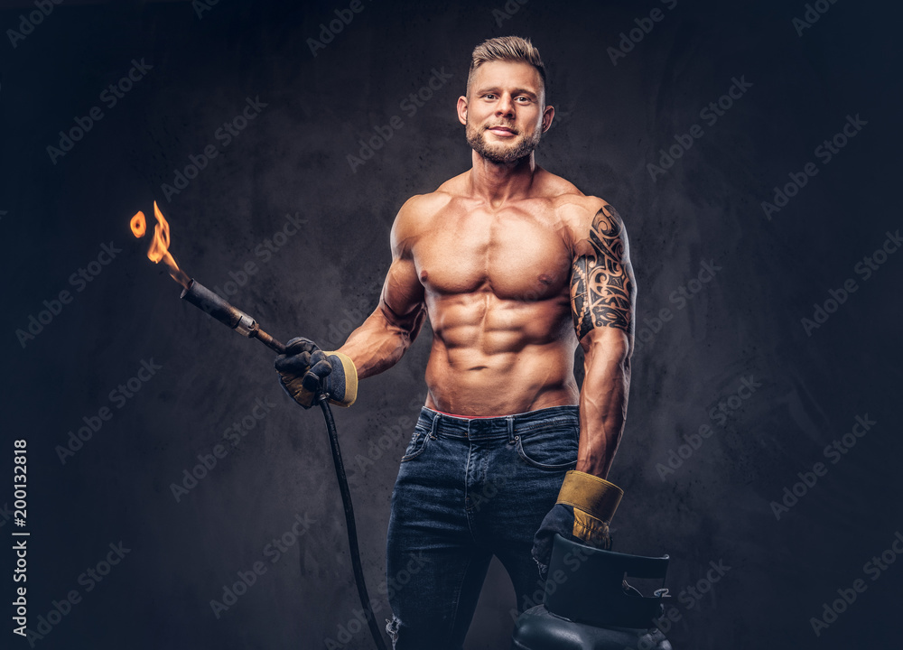 Brutal tattoed male welder with a stylish haircut and beard, with ...