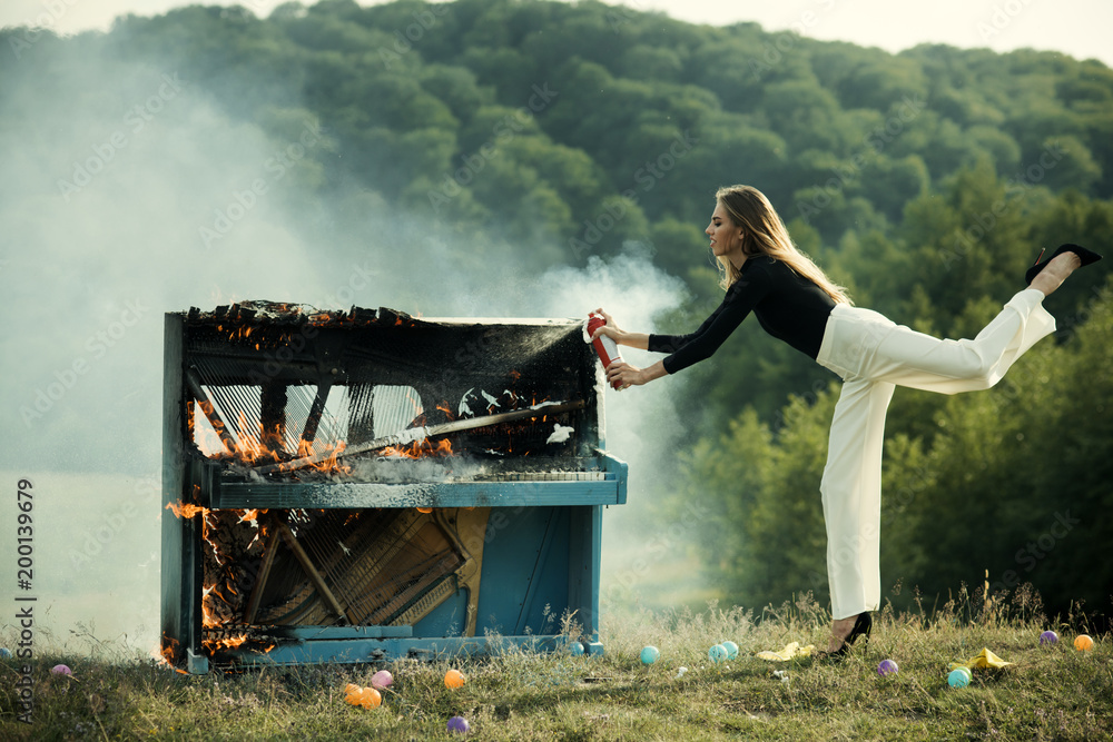 Burning piano and fashion woman at rock concert. Firefighting of girl ...