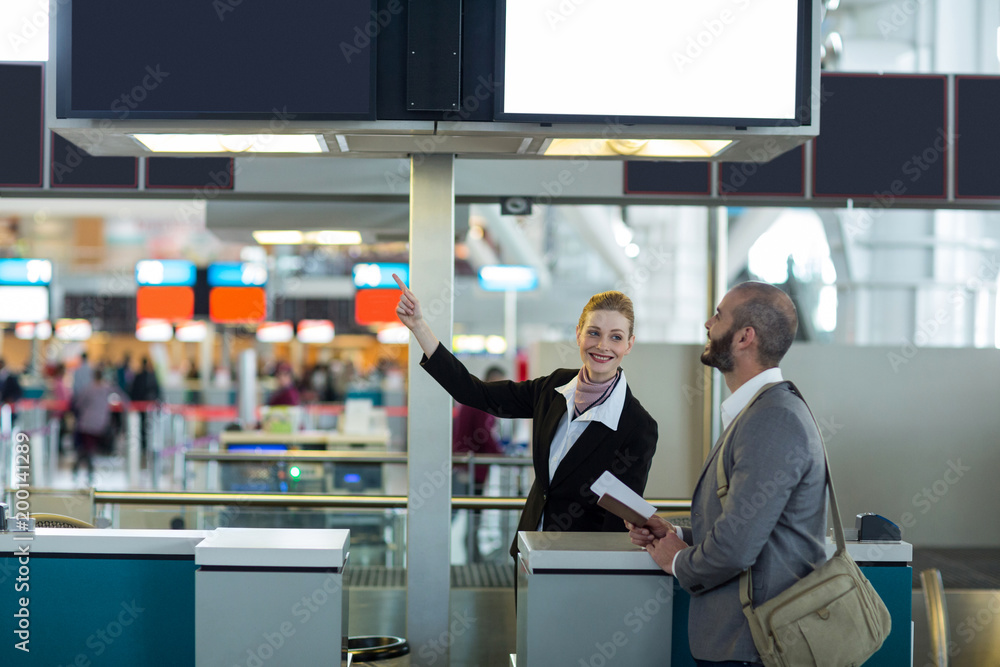 Airline check-in attendant showing direction to commuter at check-in ...