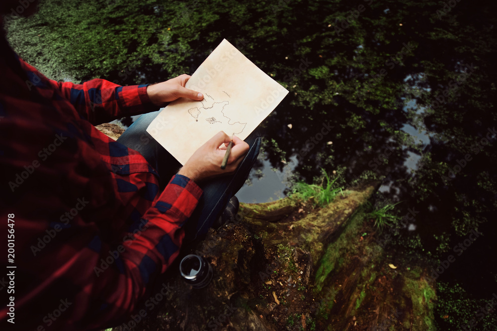 Adventurer in red checkered shirt drawing a map in search of a lost ...