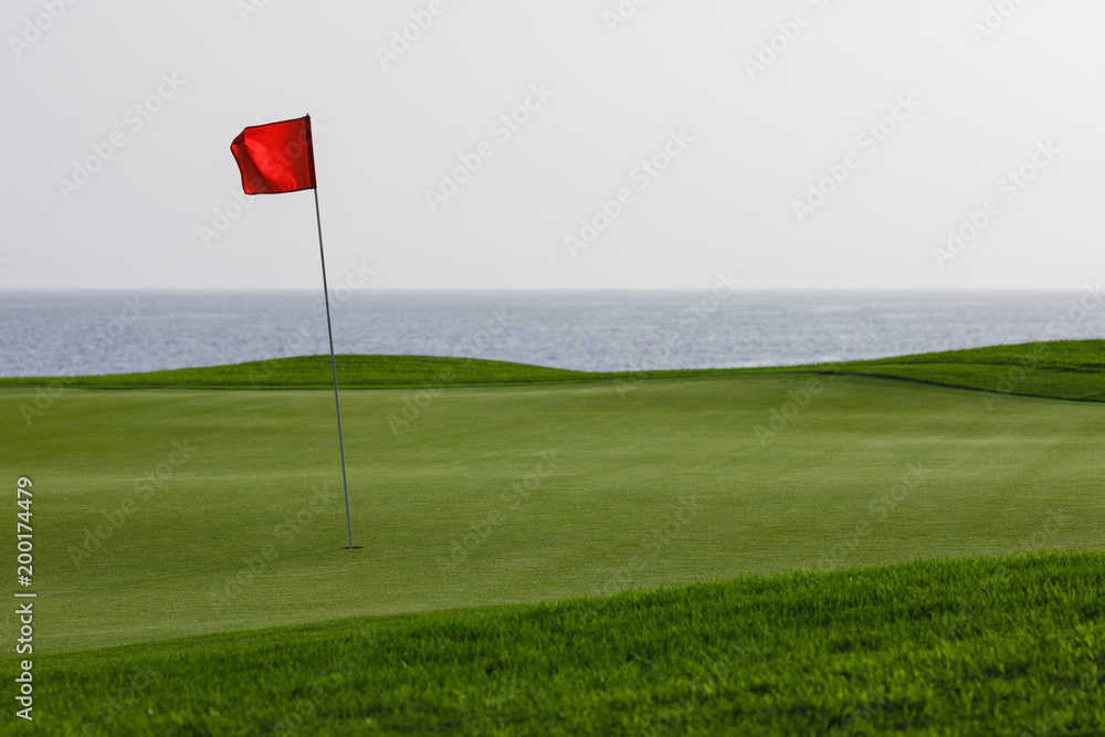 golf course with green grass and red pin flag, sea background Stock ...