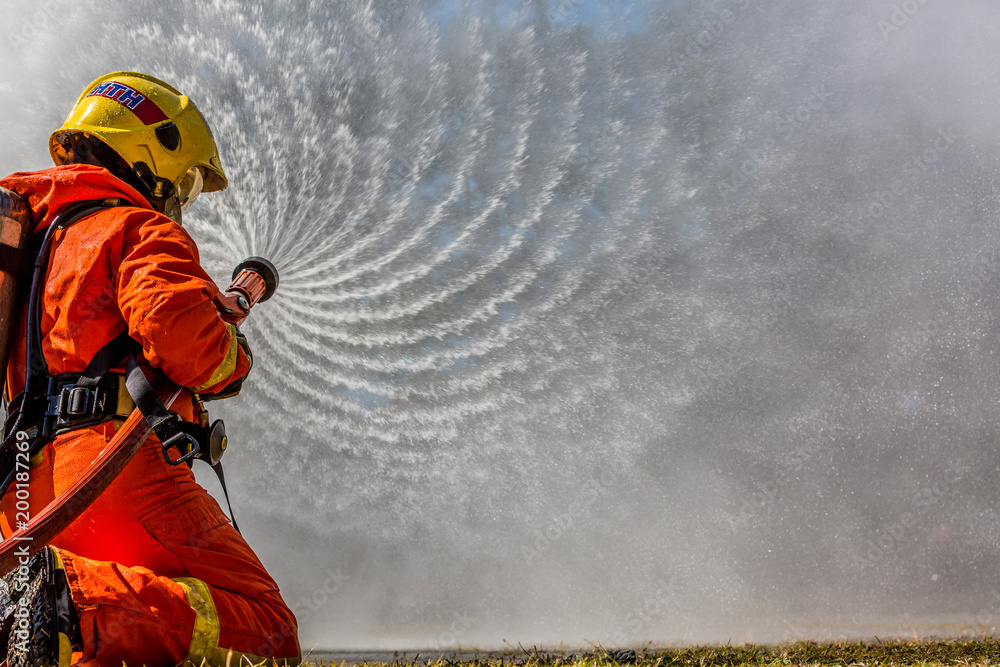 Firefighter using extinguisher and water from hose for fire fighting ...