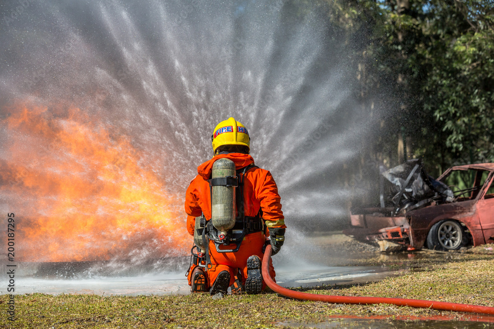 Firefighter using extinguisher and water from hose for fire fighting ...