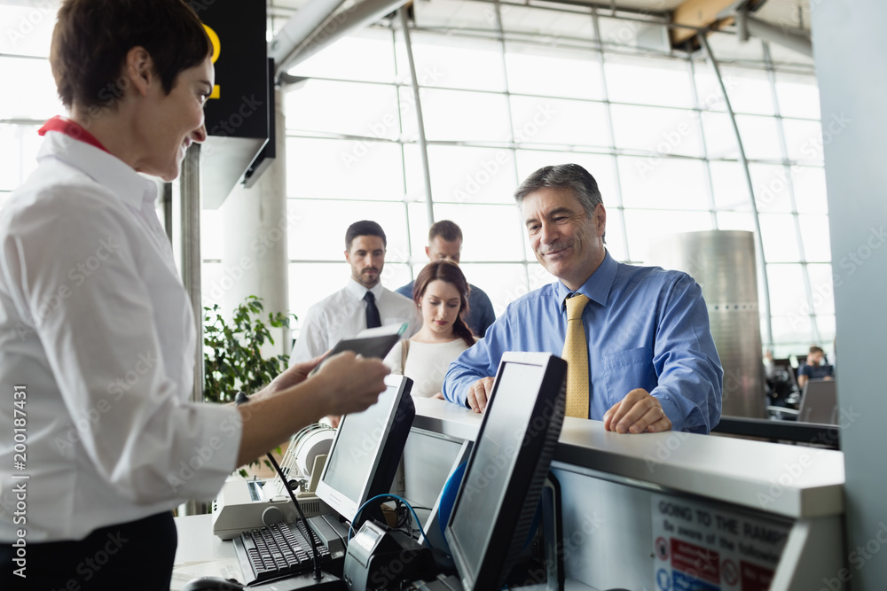Airline check-in attendant handing boarding pass to passenger Stock ...