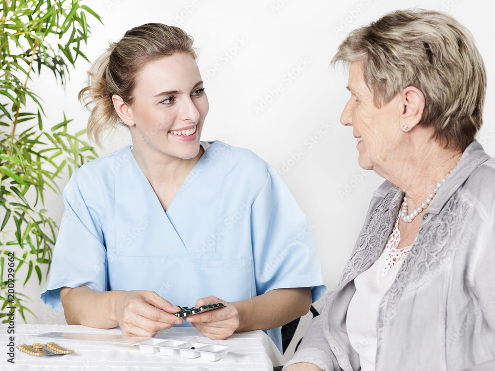 Pflegerin versorgt Seniorin mit Tabletten Stock-Foto | Adobe Stock