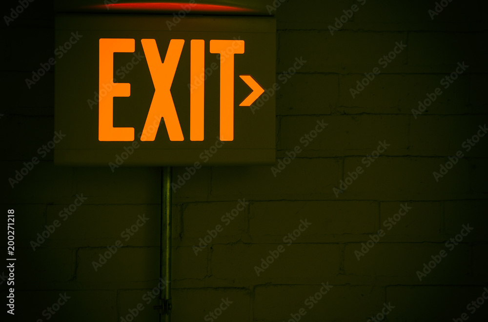 exit sign on a wall indoors. luminous exit sign with arrow in the dark ...