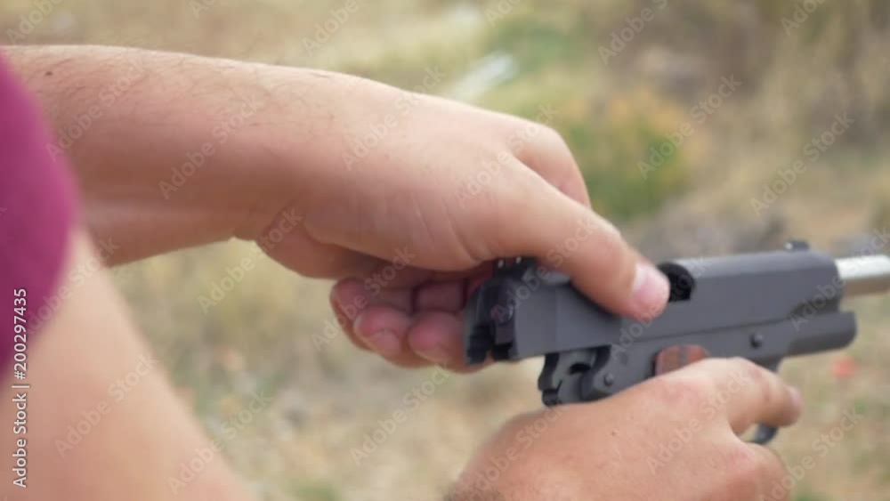 Man loading a handgun in slow motion. Closeup of a male inserting a ...