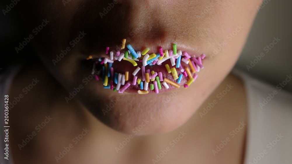 A woman's lips are covered of rainbow sprinkles / topping after eating ...