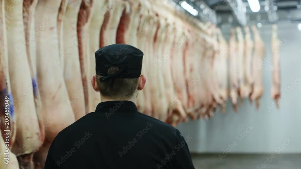 back view of walking male butcher in black uniform headwear in ...
