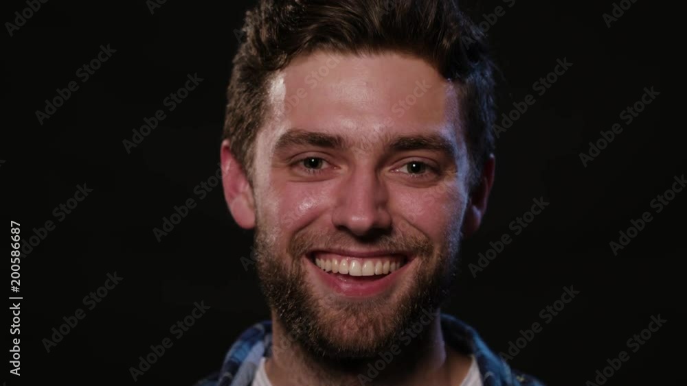 A young man's face against a black background. Close-up shot Stock ビデオ ...