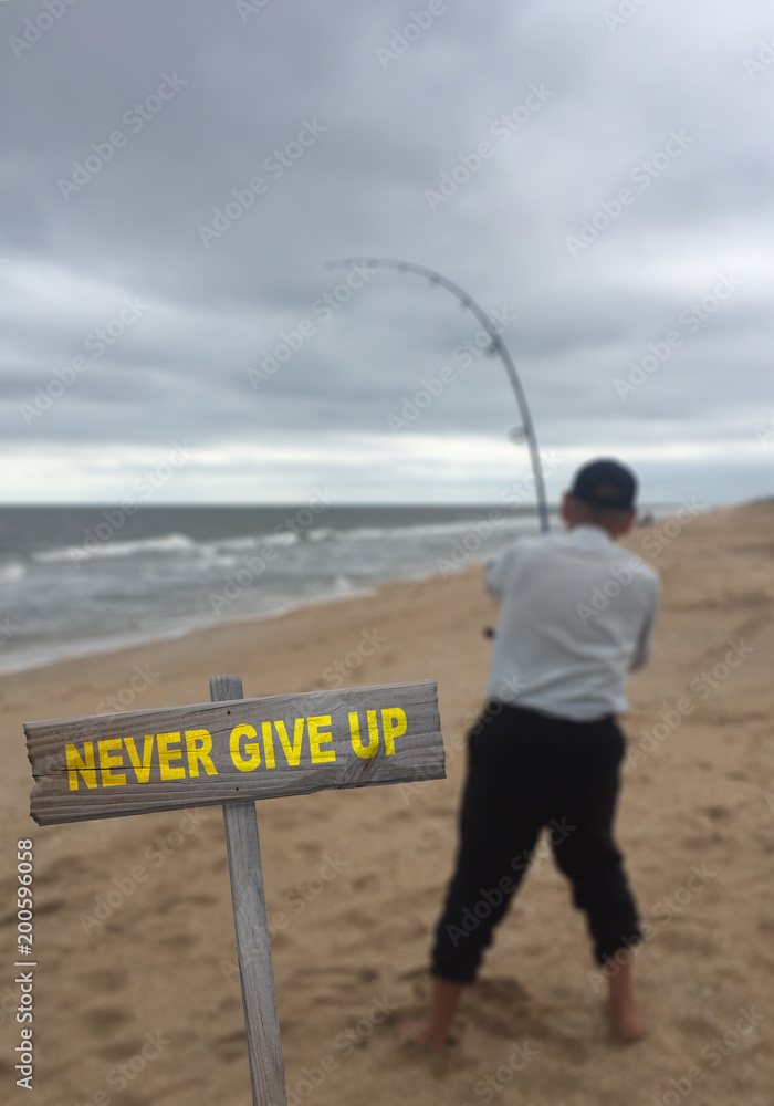 Never Give Up sign on beach background with struggling fisherman Stock ...