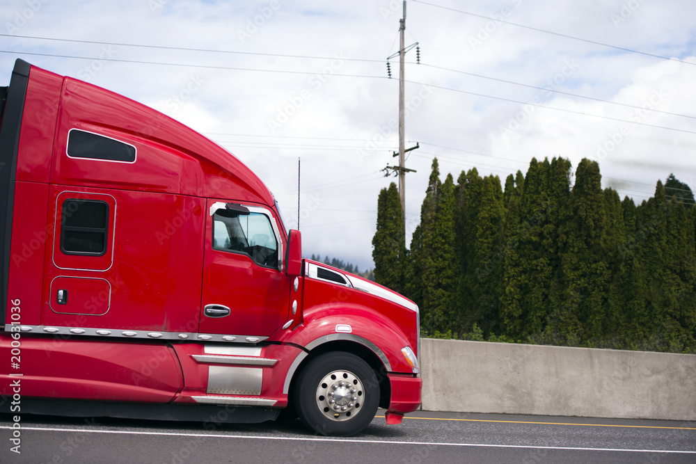 Foto de Profile of big rig red high cab semi truck tractor running on ...