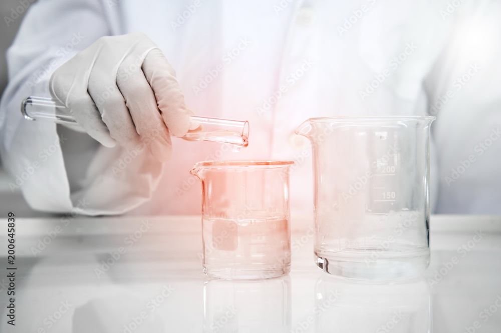 researcher in white lab coat holding cylinder and poring water into ...
