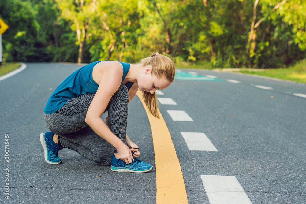 Female runner tying her shoes preparing for jogging outside .Young ...