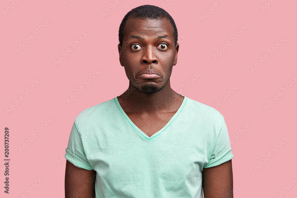 Headshot of stunned displeased African American male curves lips as ...