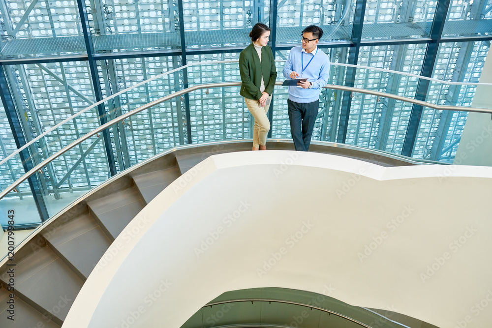 Attractive young manager and her male colleague standing on spiral ...