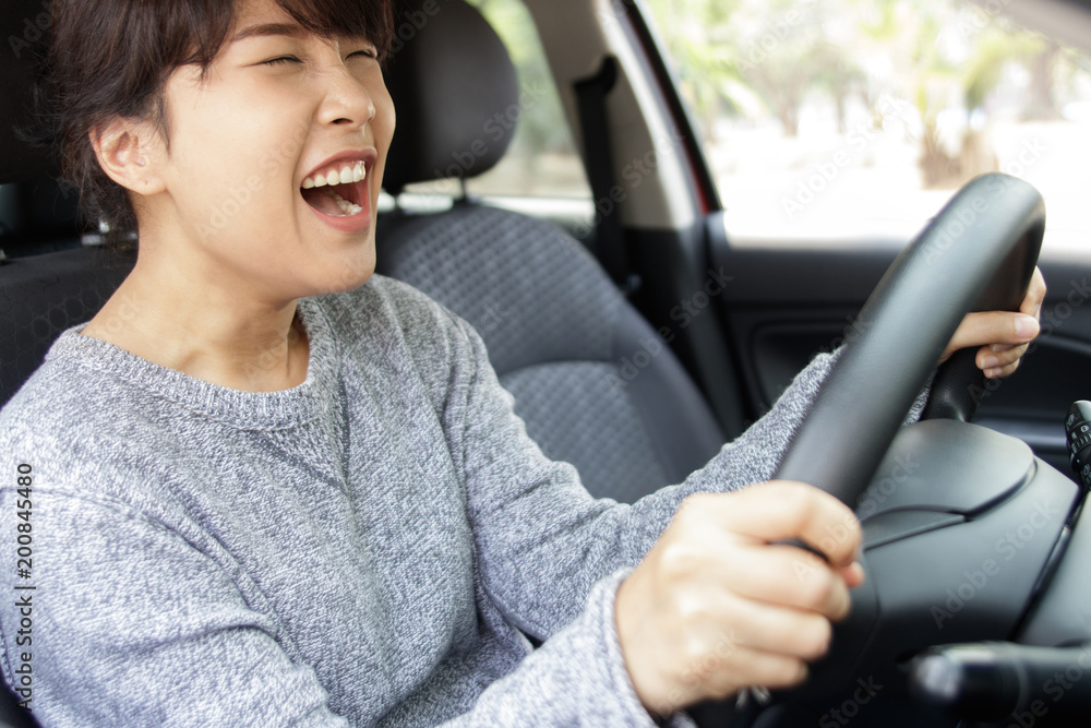 Portrait of young asian woman driving a car with shocked expression ...