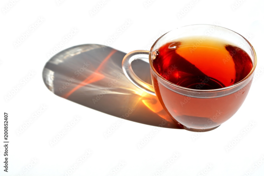 Hot black tea in transparent glass cup with long rainbow shadow in ...