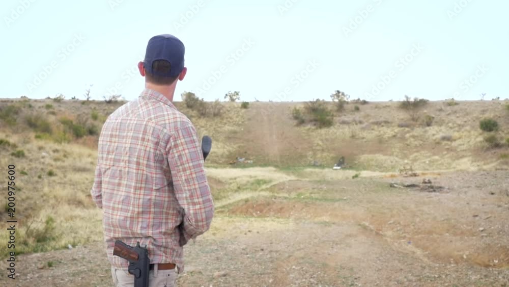 Video Stock Wide shot of a man shooting a pump action shotgun at a ...
