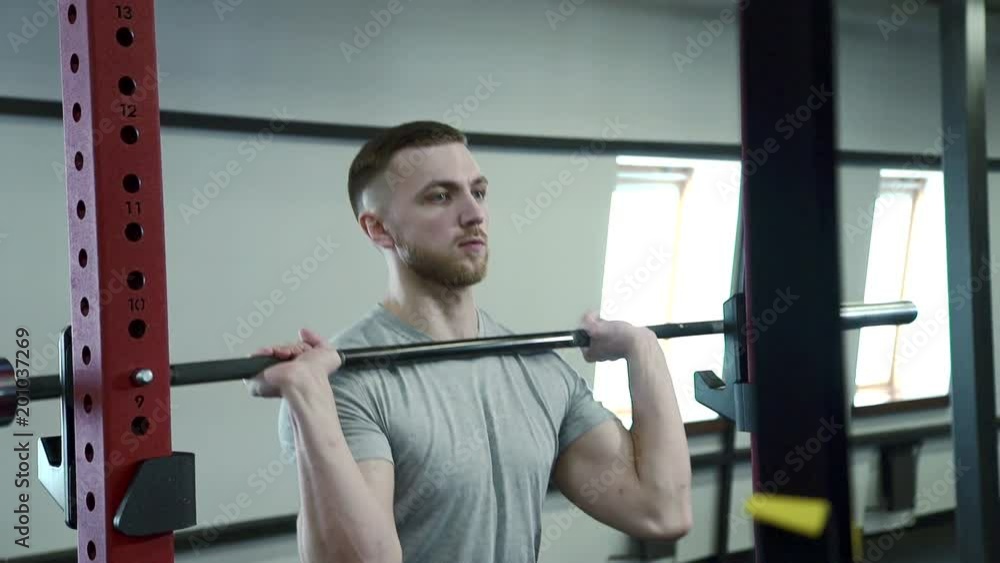 Man in workout at the gym takes a rod and begins to lift the weight ...