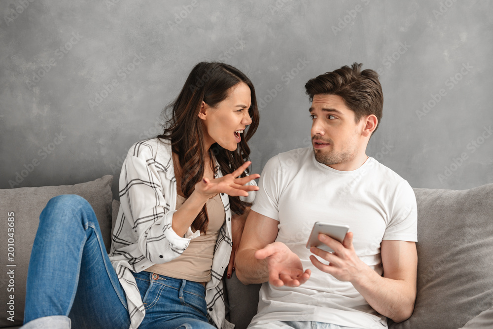 Fighting couple sitting together on sofa at home while woman shouting ...