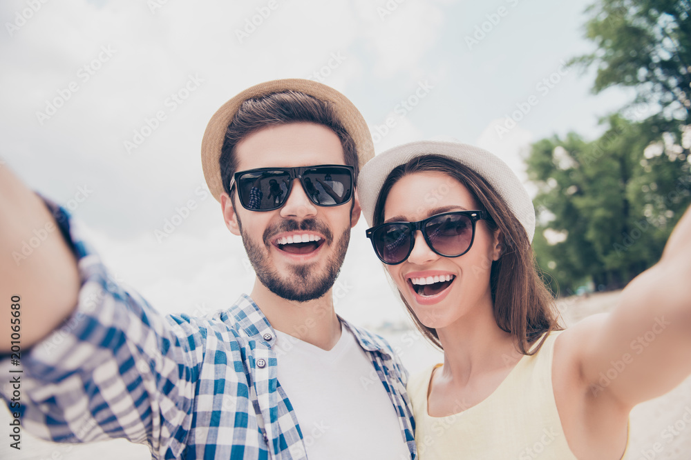 Cheerful glad positive couple in caps shooting self portrait of front ...