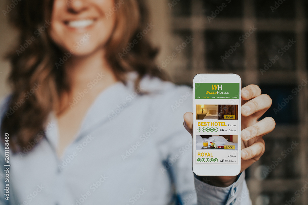 Smiling white caucasian woman holding mobile phone with hotel booking ...