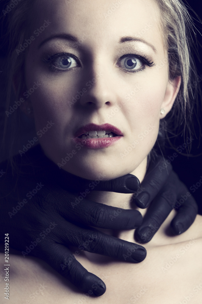 Frightened blonde woman grabbed by black hands on her neck to strangle ...
