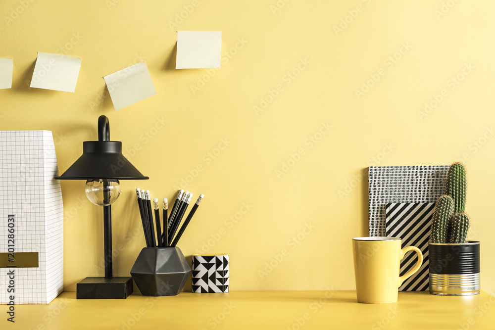 Yellow desk with cacti, office accessories, sticky notes and lamp ...