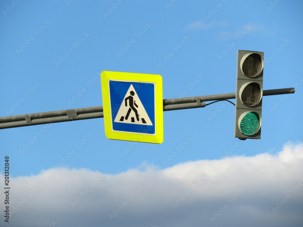 Pedestrian crossing sign and green traffic light on blue cloudy sky ...