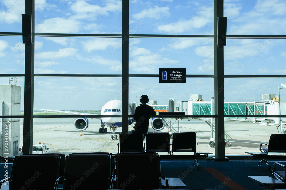 man alone at the airport on a charging electronic point before taking a ...