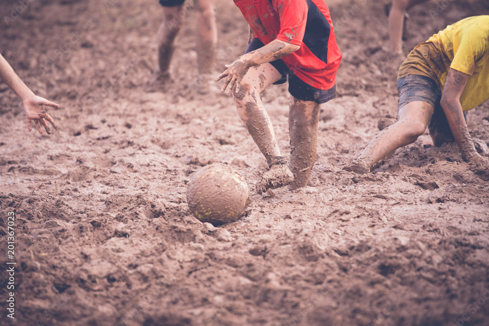 Two boys playing football in the mud with their friends Stock Photo ...