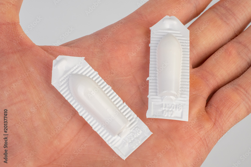 Medical hand with suppository vaginal rectal pills medicine on a white ...