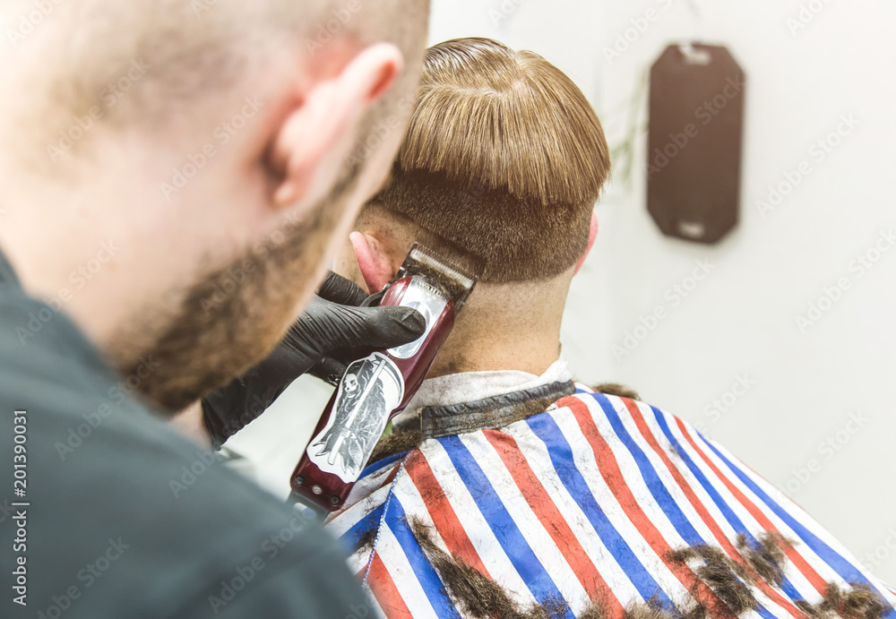 Foto de Men's haircut in barbershop. Master barber does a haircut to ...