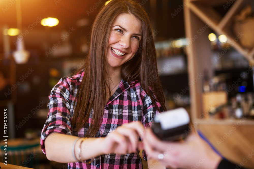Young happy cute girl is typing in her PIN number of a bank card to pay ...