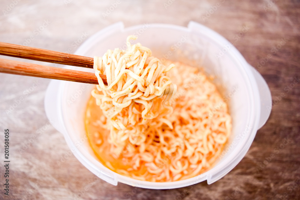Hand uses chopsticks to pick up tasty noodles, instant noodles in a ...