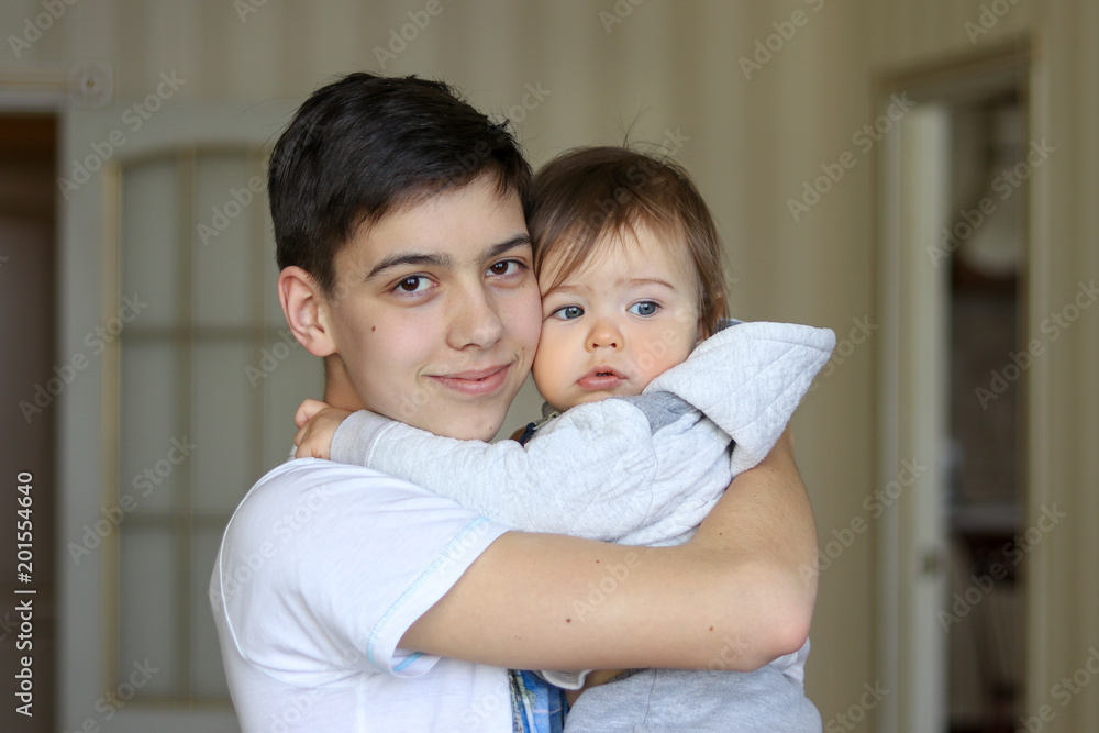 Happy teenager boy and his cute little brother hugging each other ...