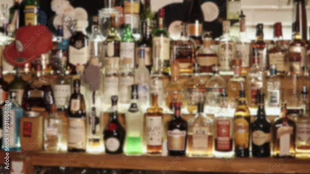 Spirit drinks in bottles in a bar of night club. Camera is showing an ...