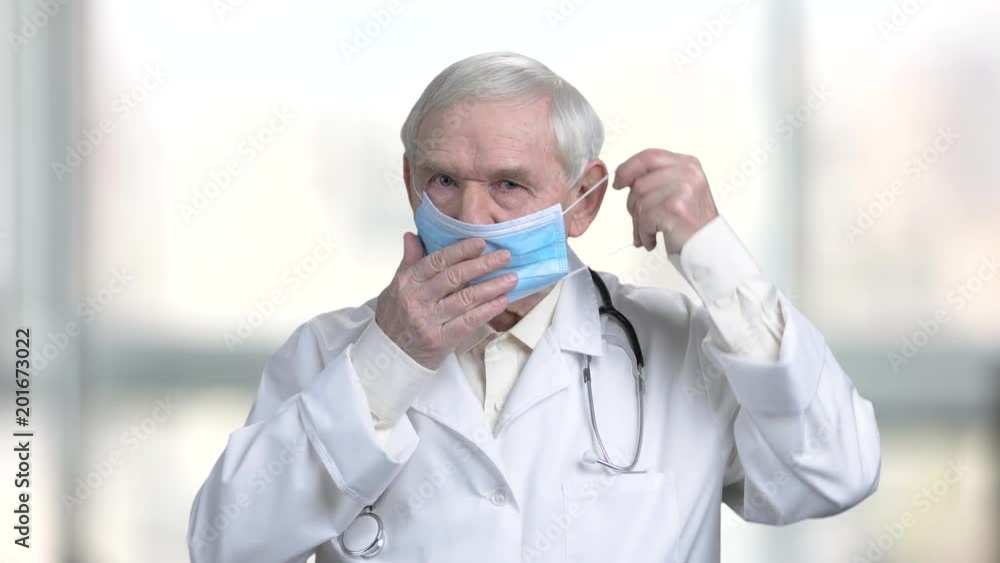 Old doctor putting on blue medical mask. Doctor wear mask in blurred ...